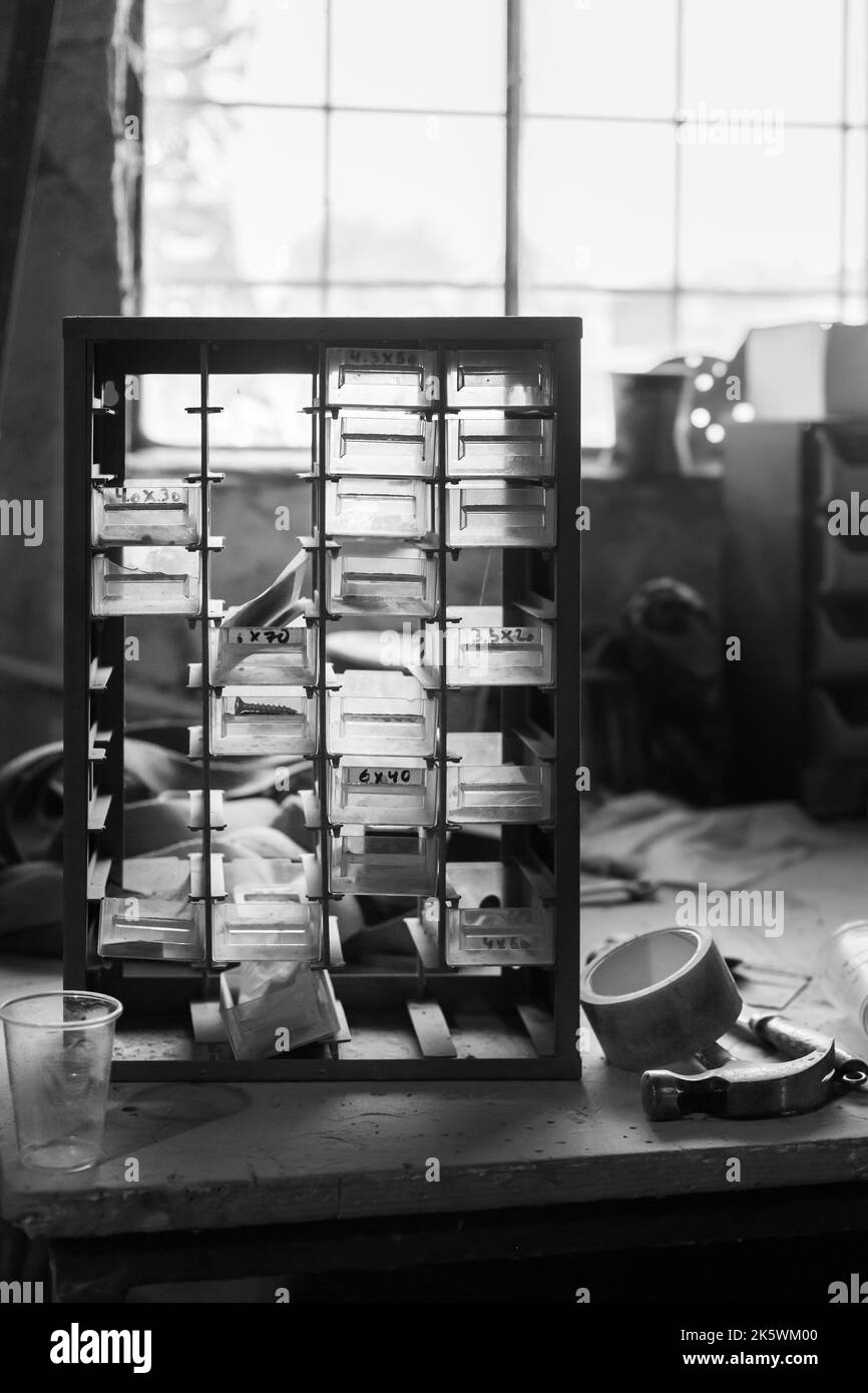 A vertical gray-scale shot of plastic drawers for screws placed on a ...