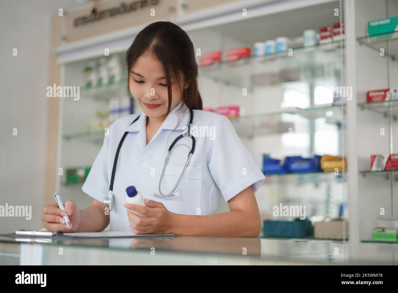 Medicine and health concept, Female pharmacist hold pill bottle and write prescription in ...