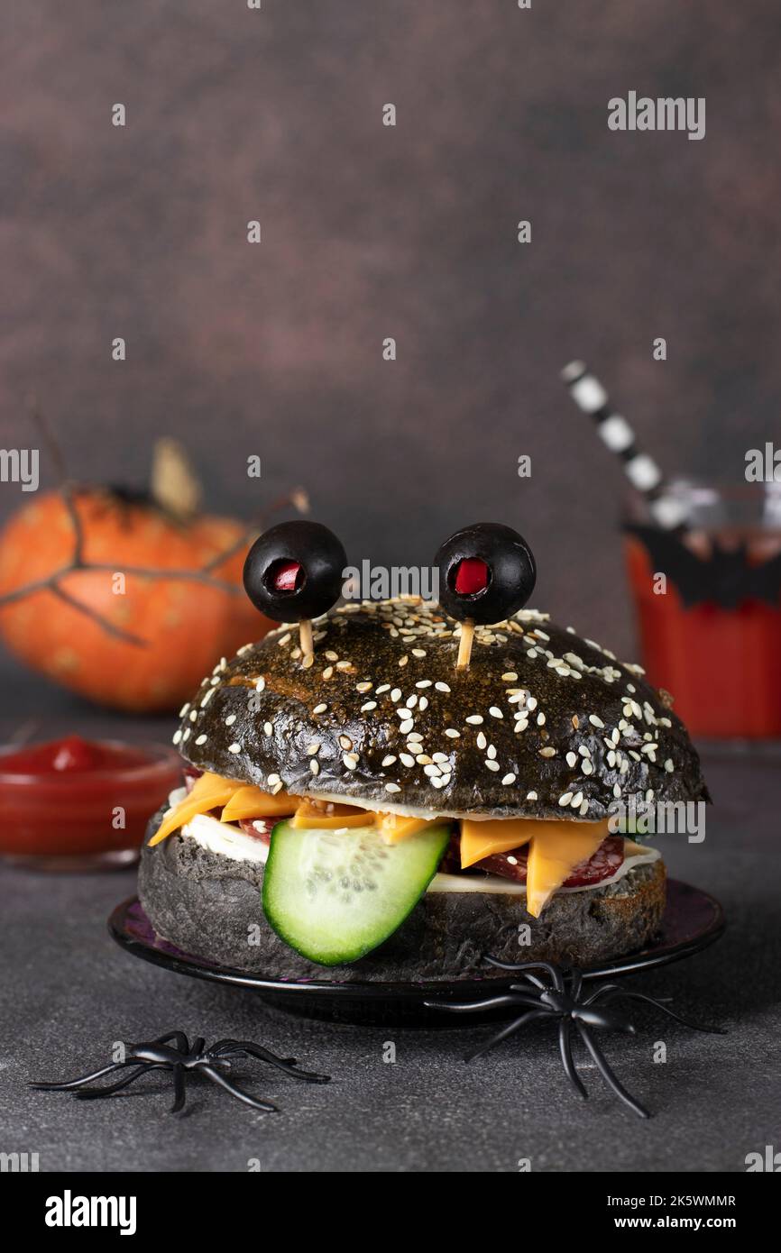 Monster sandwich with black bun, sausage, cheese, cucumber and olive ...