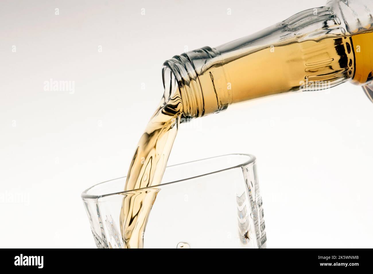 pouring bourbon whiskey into a glass from the neck of a bottle close-up ...