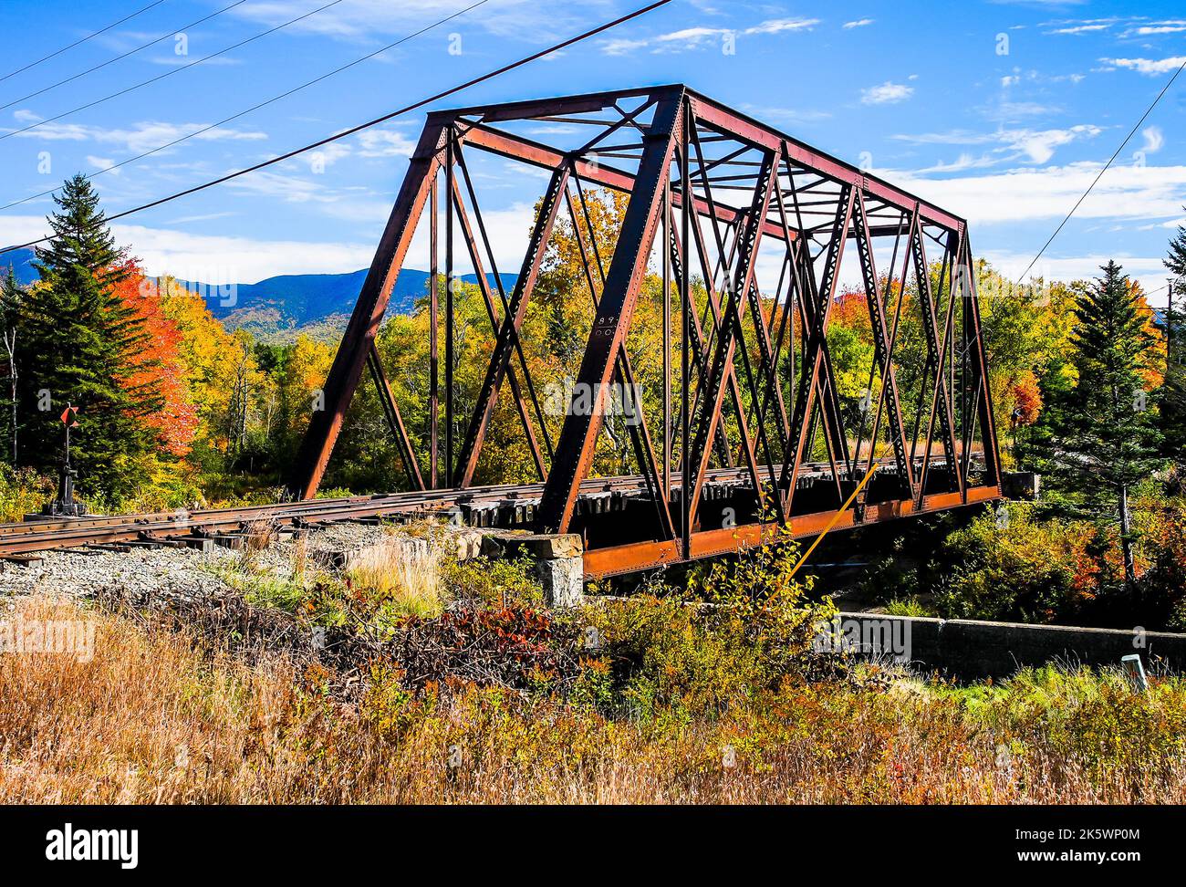 Railroad iron bridge with autumn colors in nice sunny day with blue sky ...