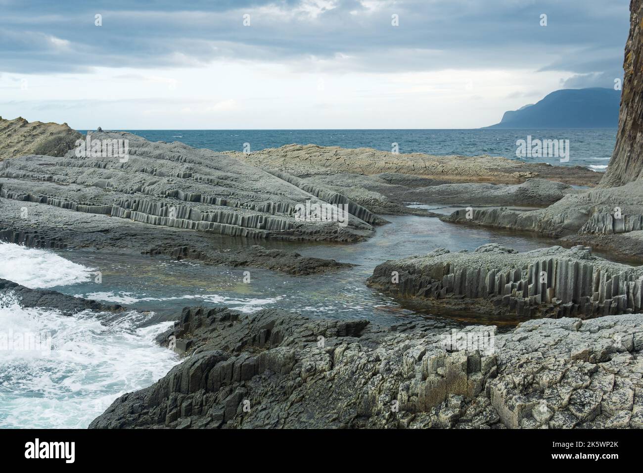 rocky seashore formed by columnar basalt against the backdrop of a ...