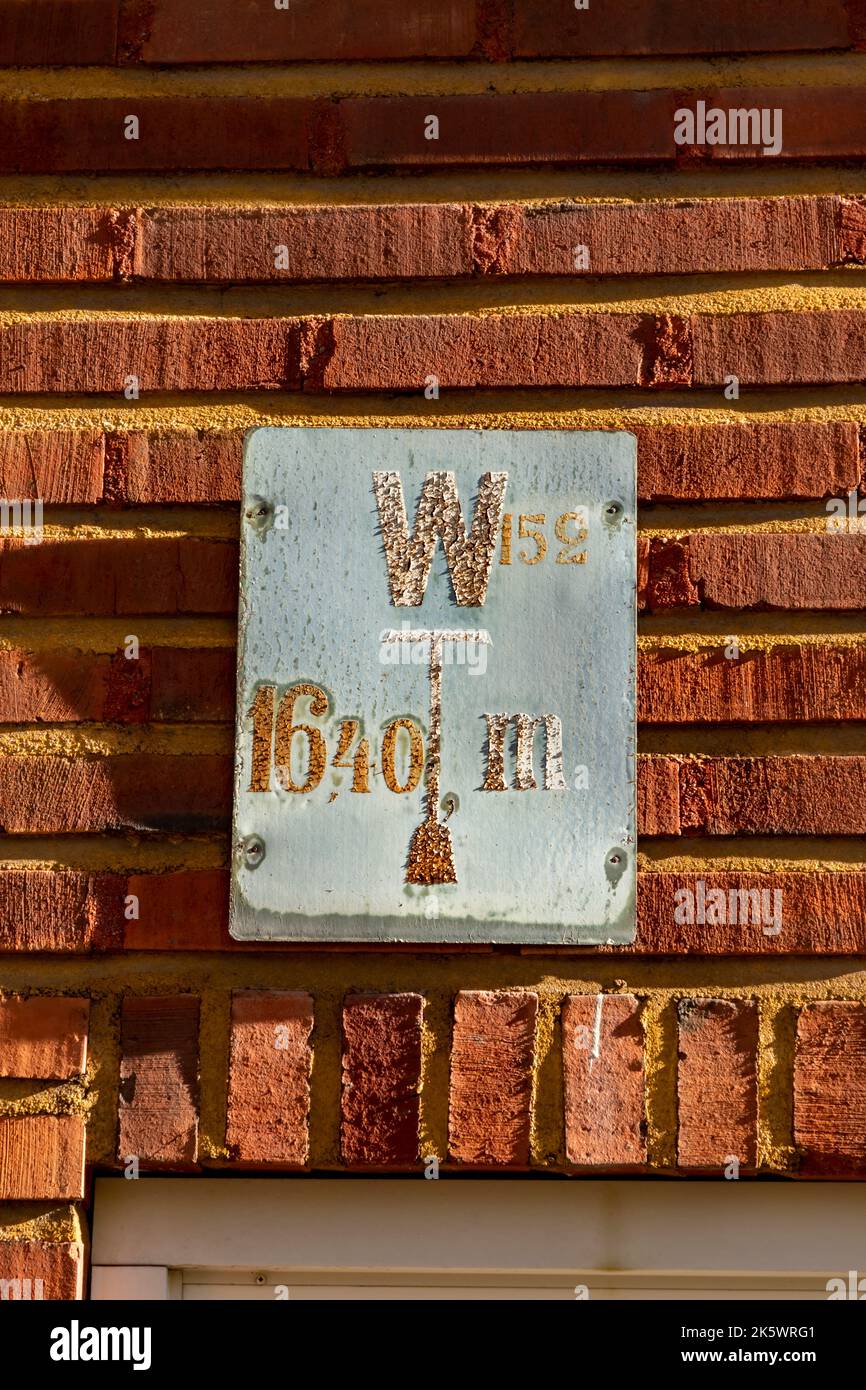 Vintage fire hydrant sign with paint peeling, on a brick exterior wall ...