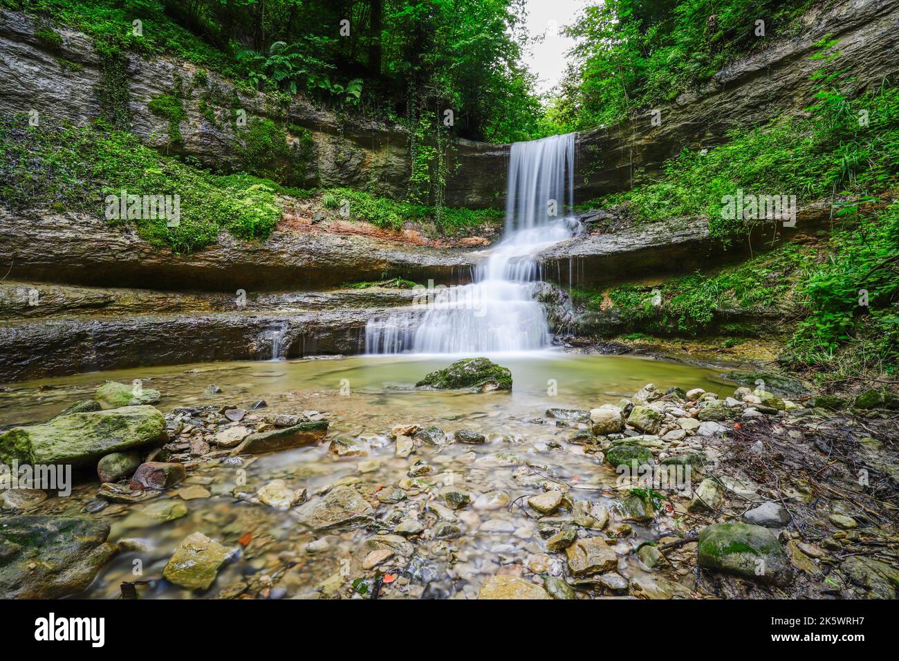 A scenic view of a waterfall streaming down in a small pond found in ...