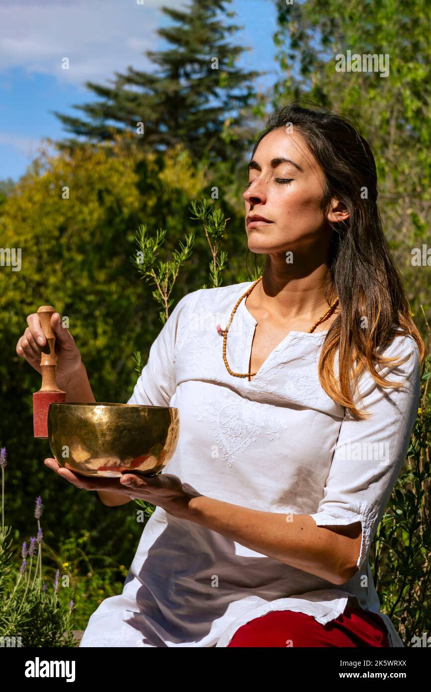 Woman playing a Tibetan singing bowl outdoors. Sound therapy ...