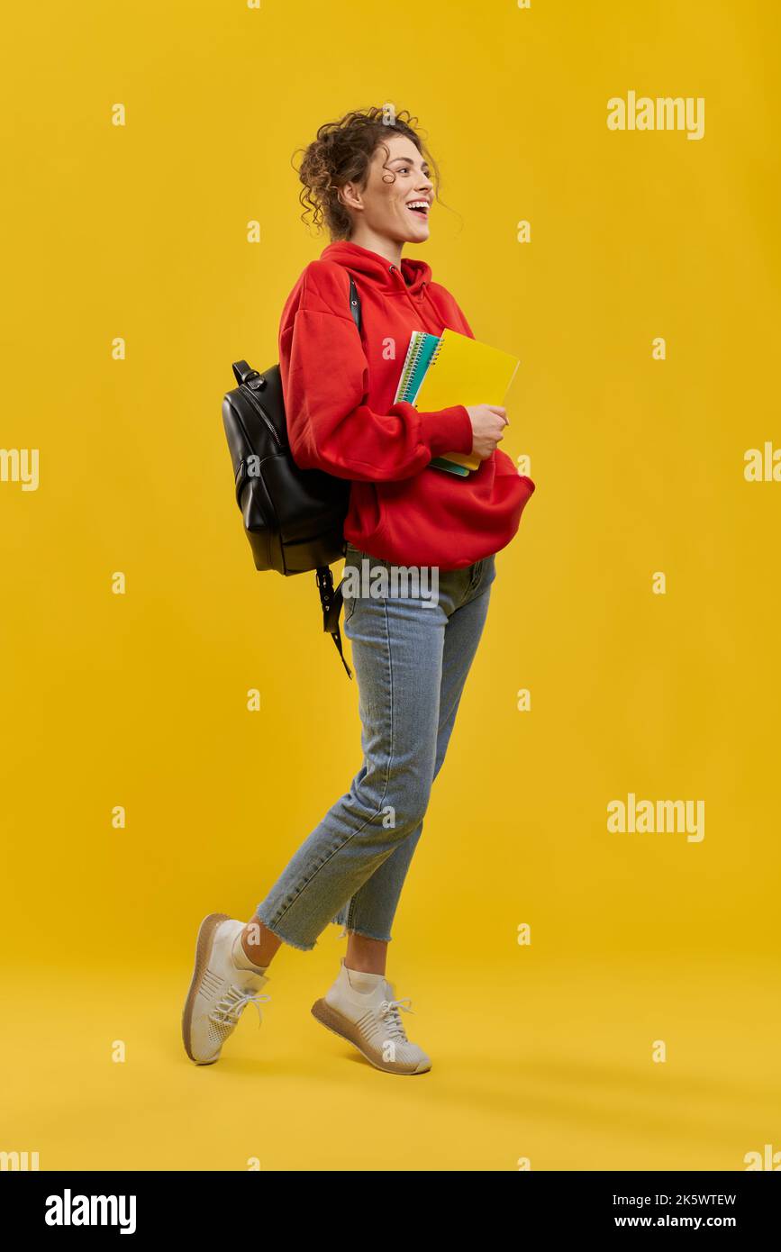 Side view of pretty female student standing, smiling at studio ...
