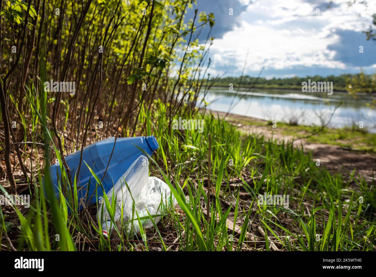 Abandoned garbage plastic and glass waste in nature among the grass ...