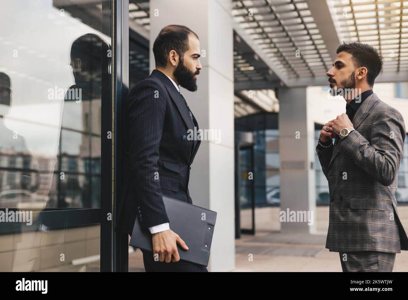 Business people outdoor meeting. Two men in suits are standing and ...