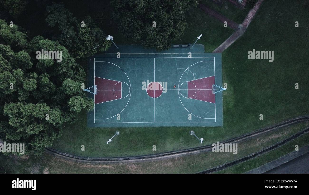 The top view of a basketball court by the grass field and trees ...