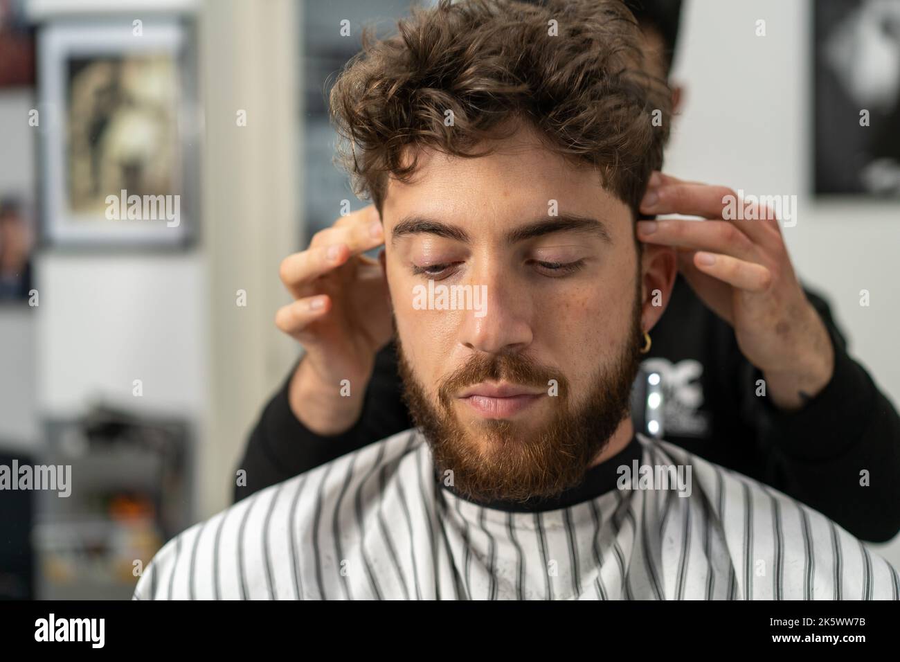 Making haircut look perfect. Young bearded man getting haircut by ...