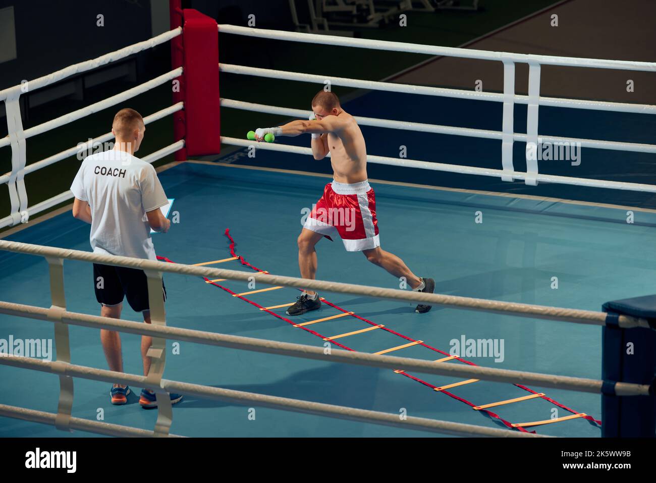 Professional boxer training with personal coach, trainer at boxing ring ...