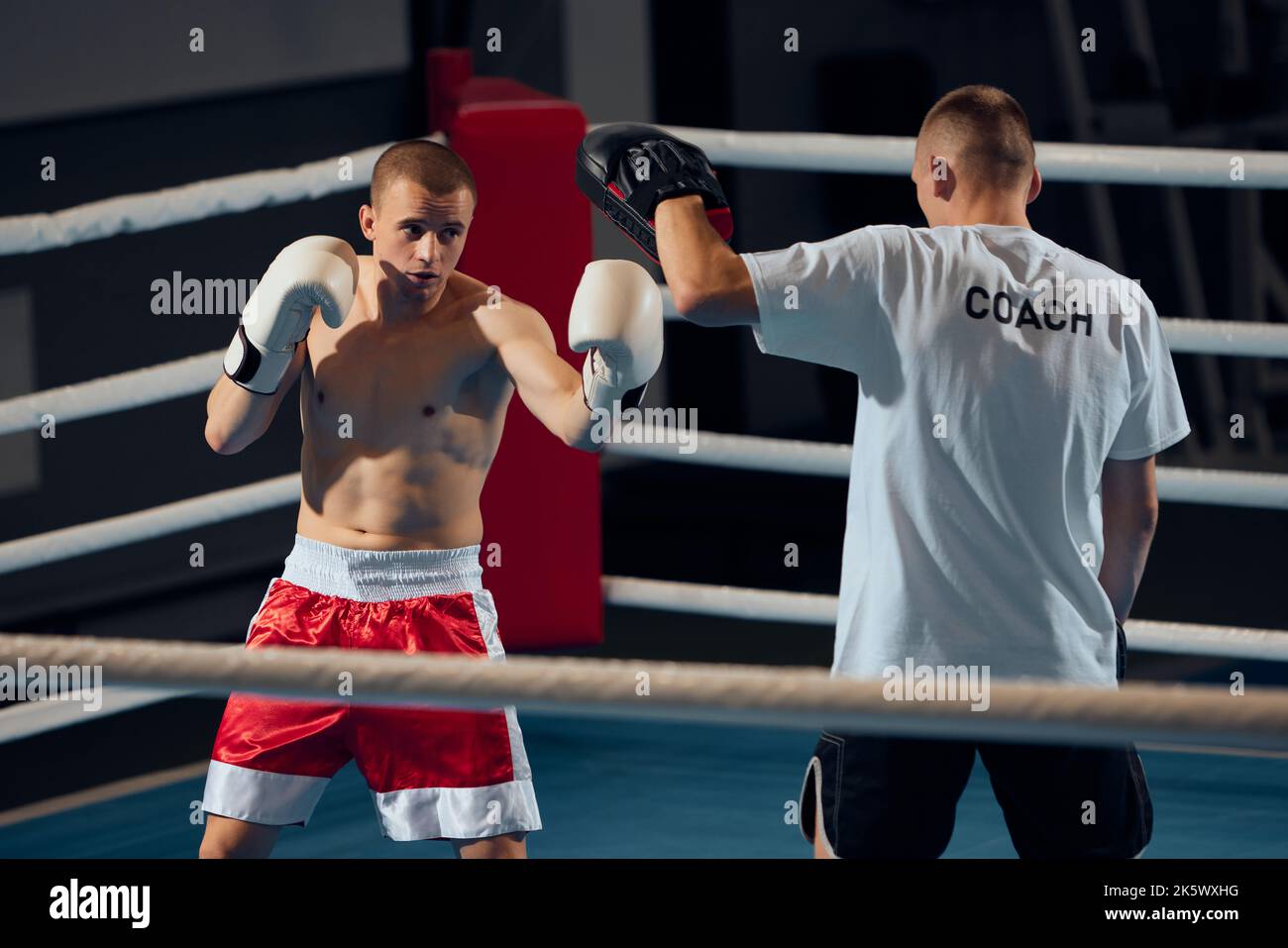 Young adult man doing boxing training with his coach. Workout at boxing ...