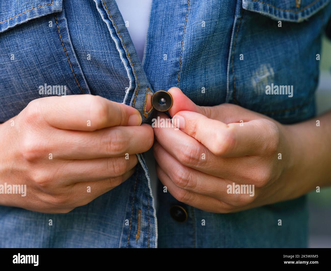 A woman hands buttoning a denim jacket. Close-up Stock Photo - Alamy