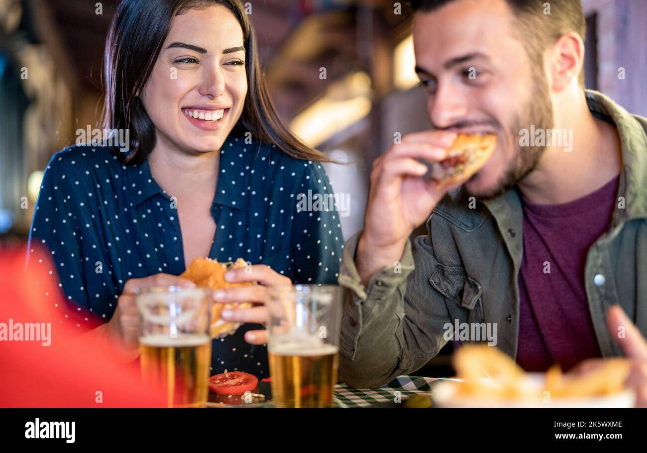 Couple in love having fun eating burger at restaurant pub - Young happy ...