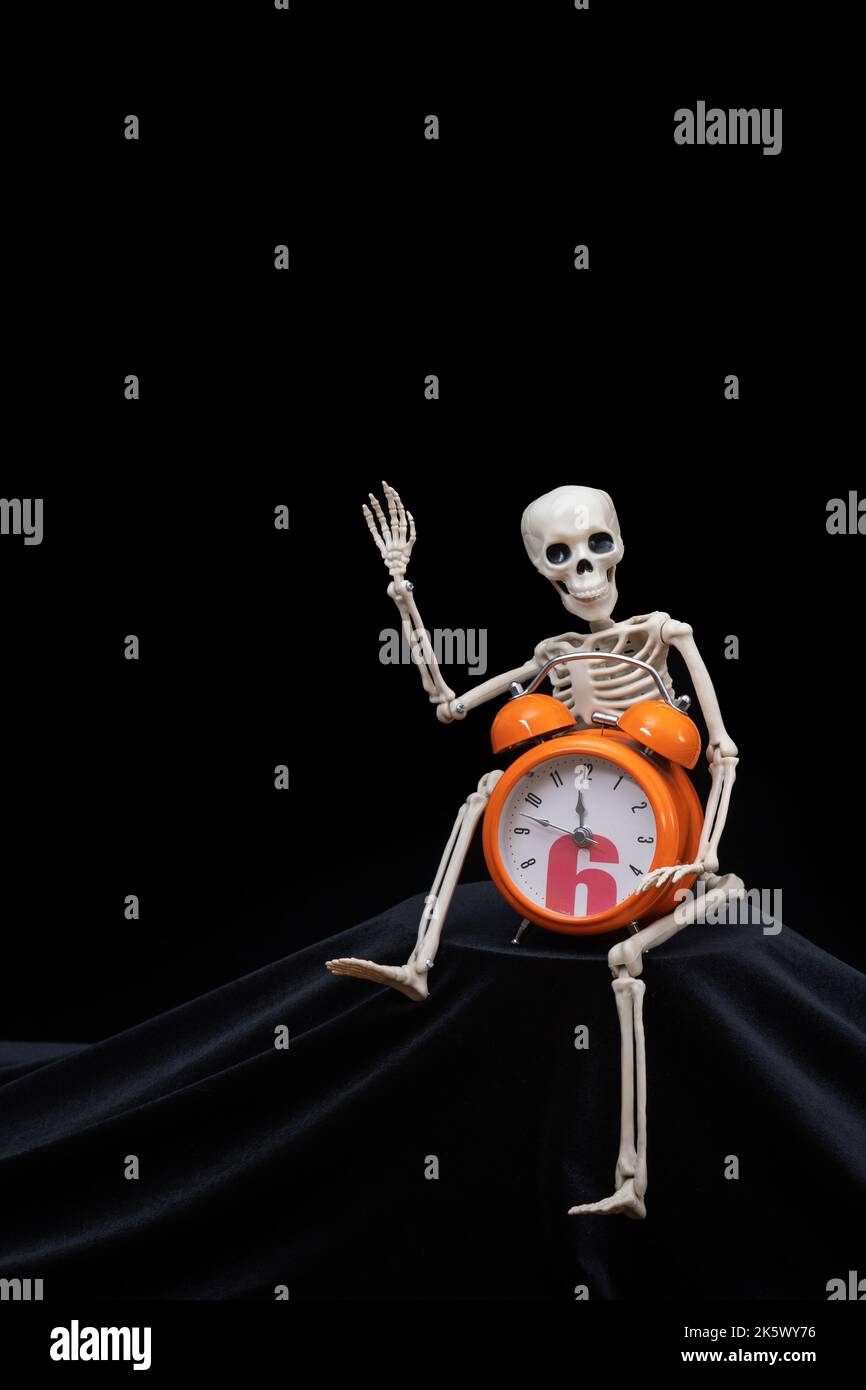 A human skeleton waving his hand, greeting holding an orange alarm ...