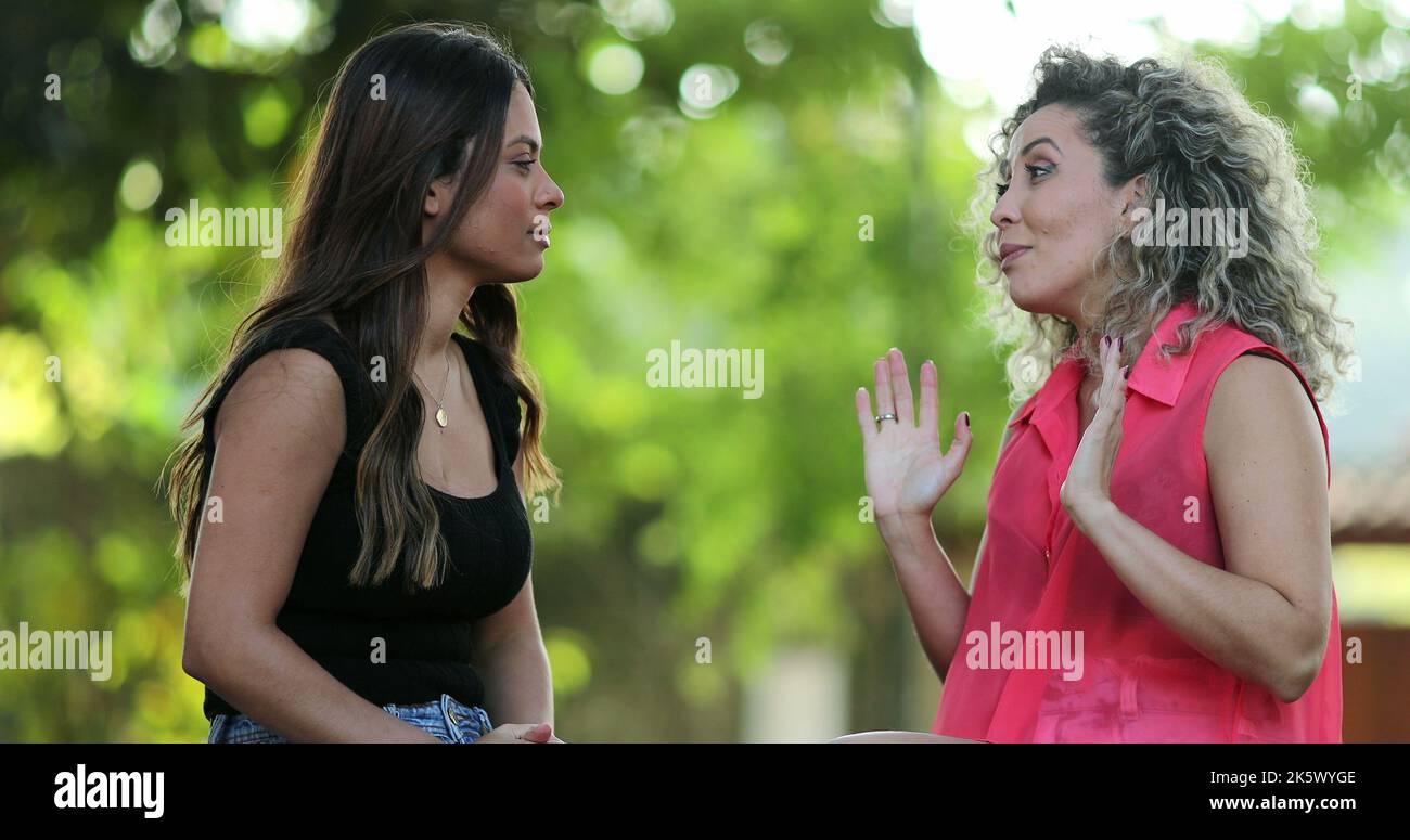 Two women chatting outside, people talking at park Stock Photo - Alamy