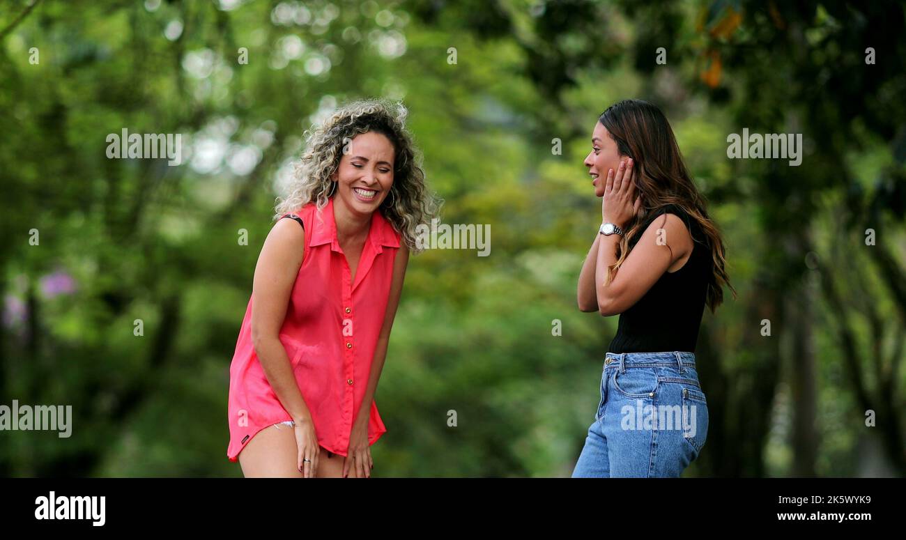 Two women in conversation outside, femal friends laughing together ...