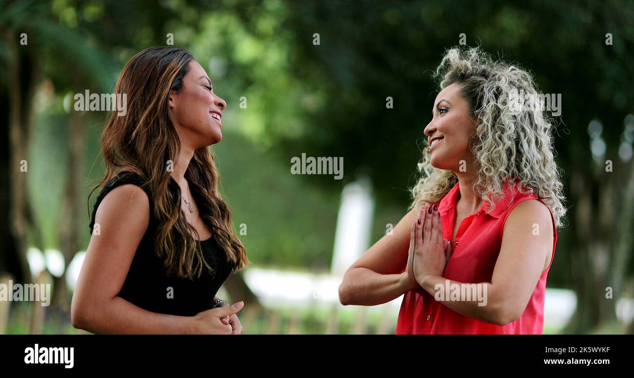 Two women in conversation outside, femal friends laughing together ...