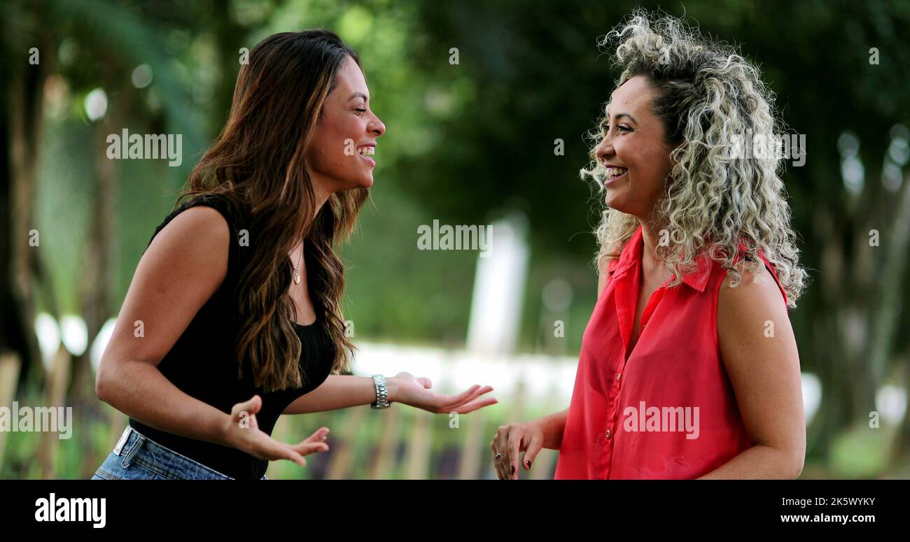 Two women in conversation outside, femal friends laughing together ...