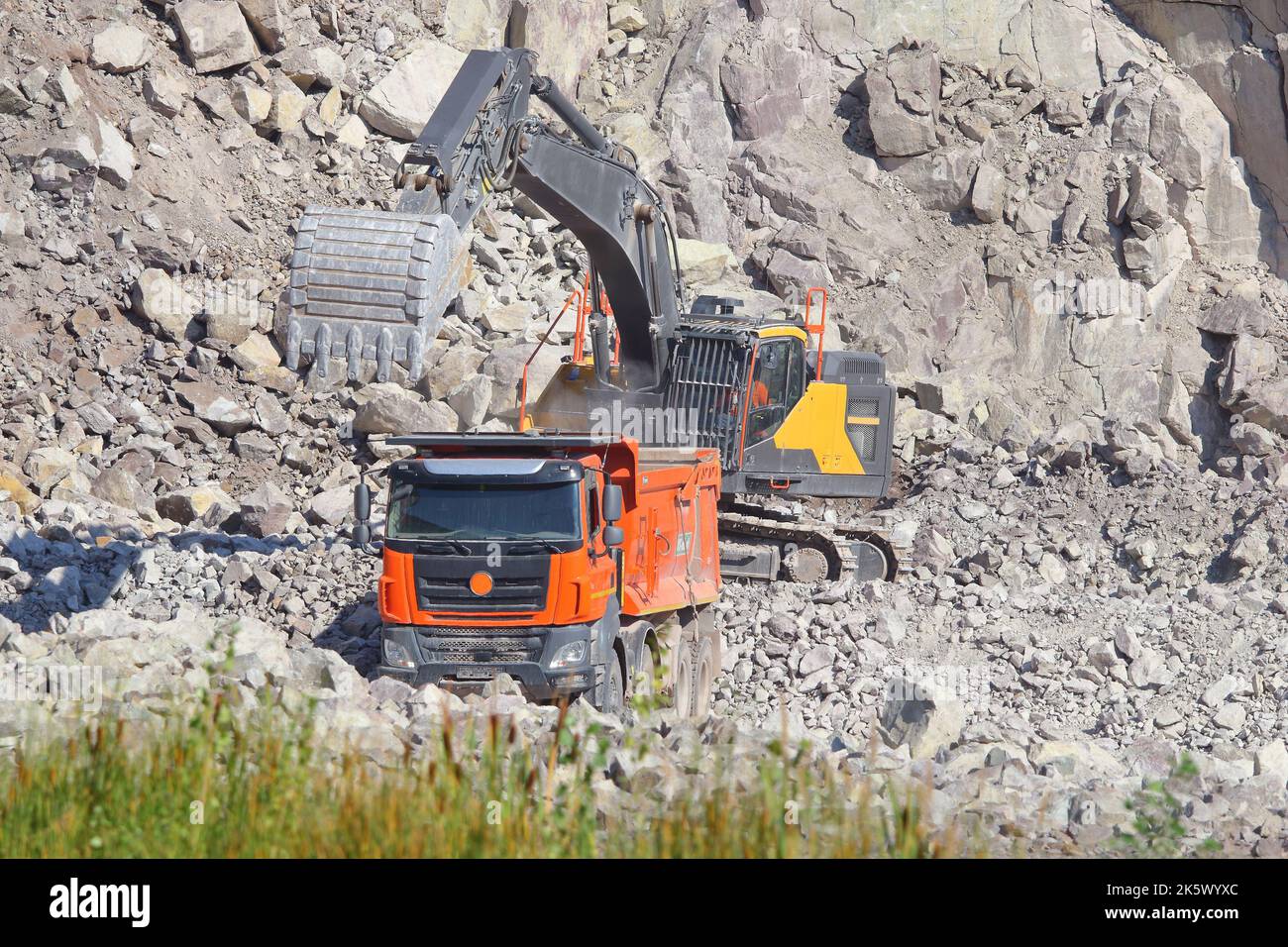The yellow hydraulic crawler excavator loading stones into an orange ...