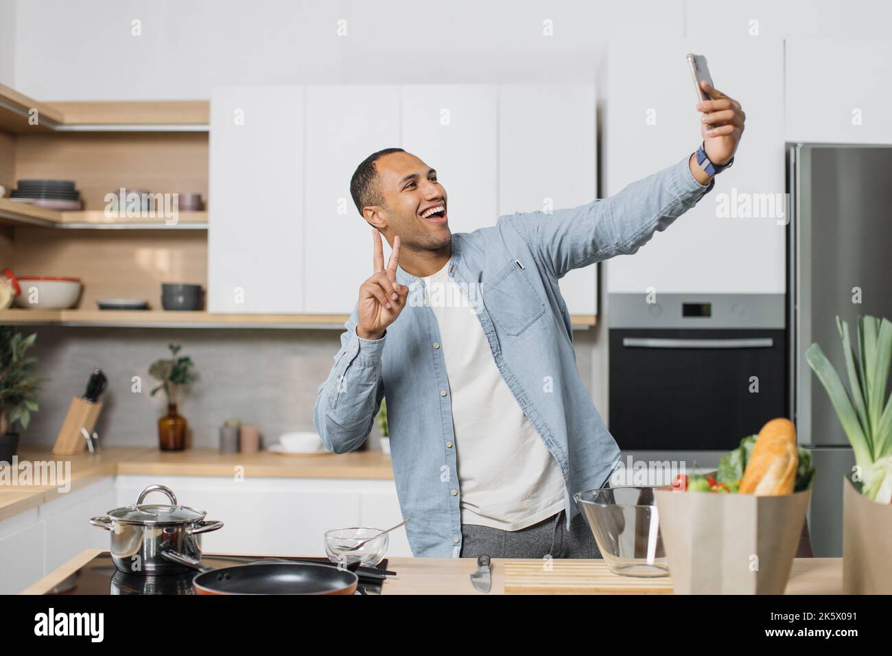 Happy young arabian man preparing dinner searching vegetable recipes ...
