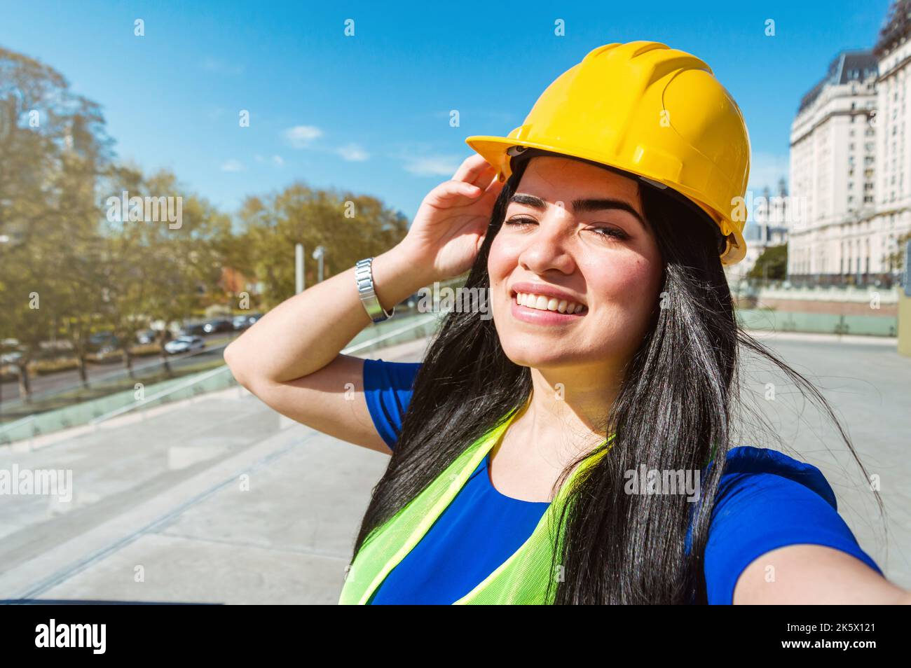 portrait of a young female engineer smiling, wearing a yellow helmet ...