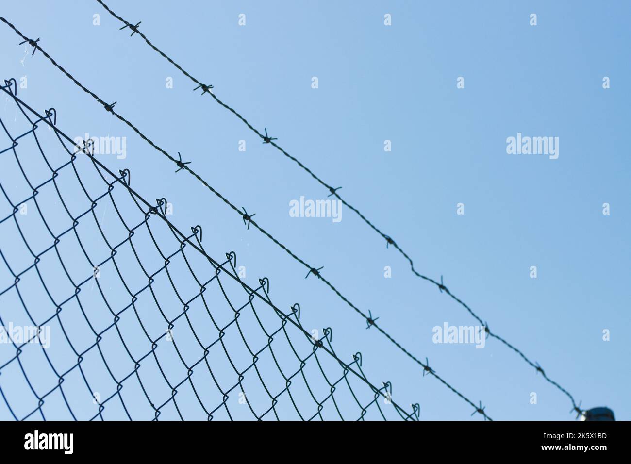Diagonal view of a fence made with metal mesh and barbed wire on top ...