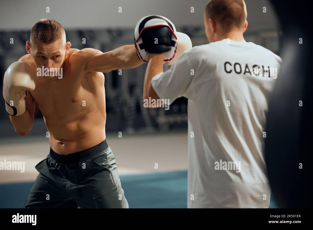 Professional boxer training with personal coach, trainer at boxing ring ...