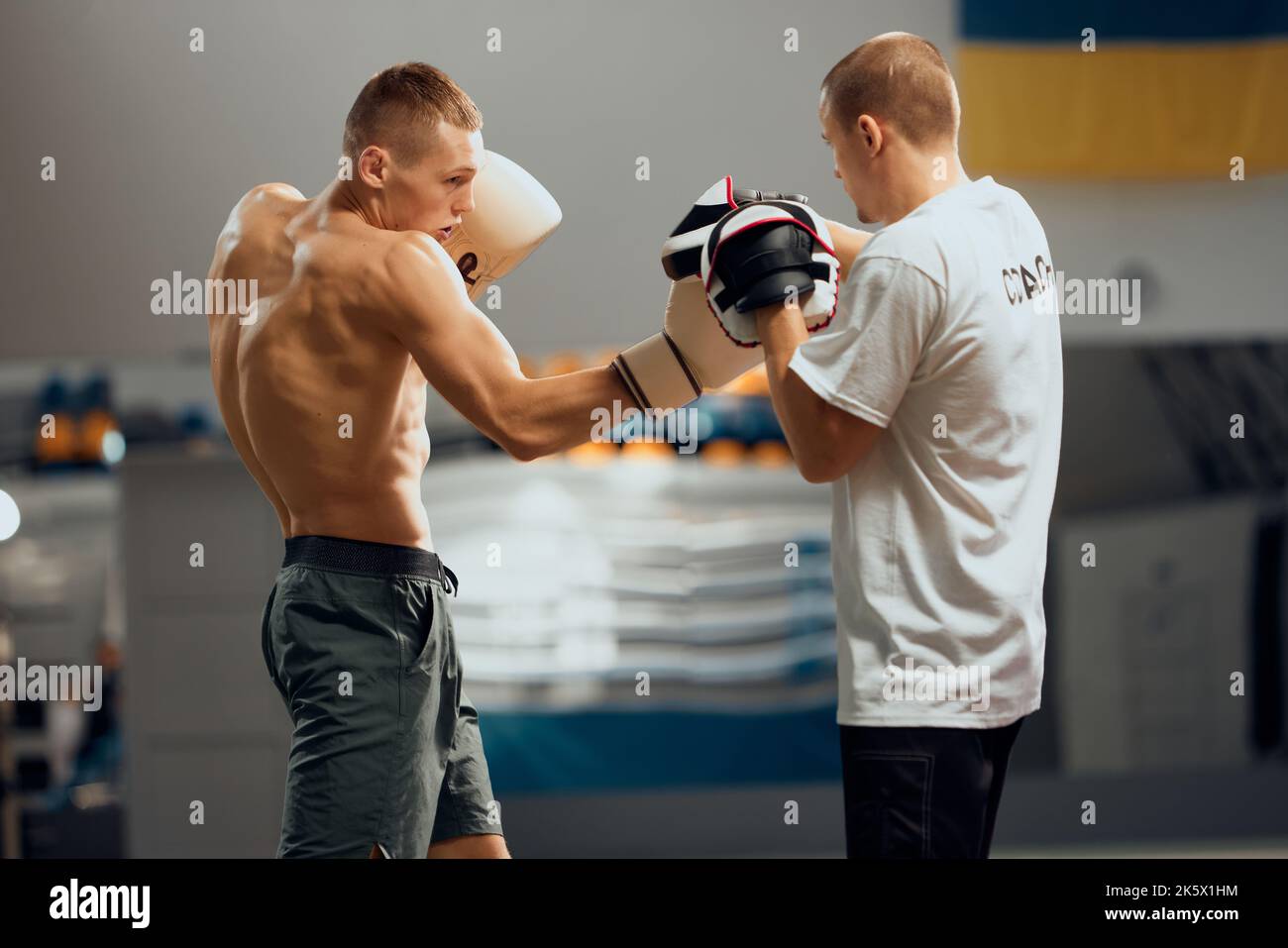 Professional boxer training with personal coach, trainer at boxing ring ...