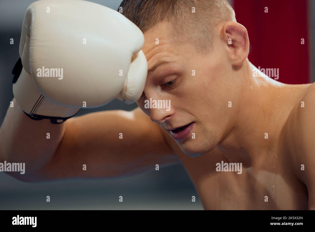 Young athlete, male boxer on break from exercise and training on the ...