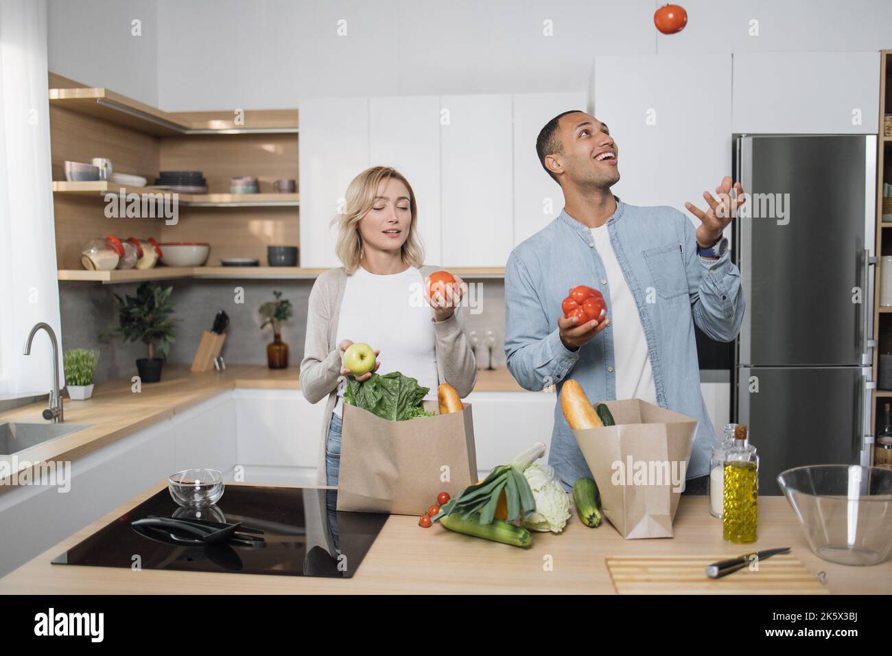 Arabian young man and woman in casual attire cooking together at home ...