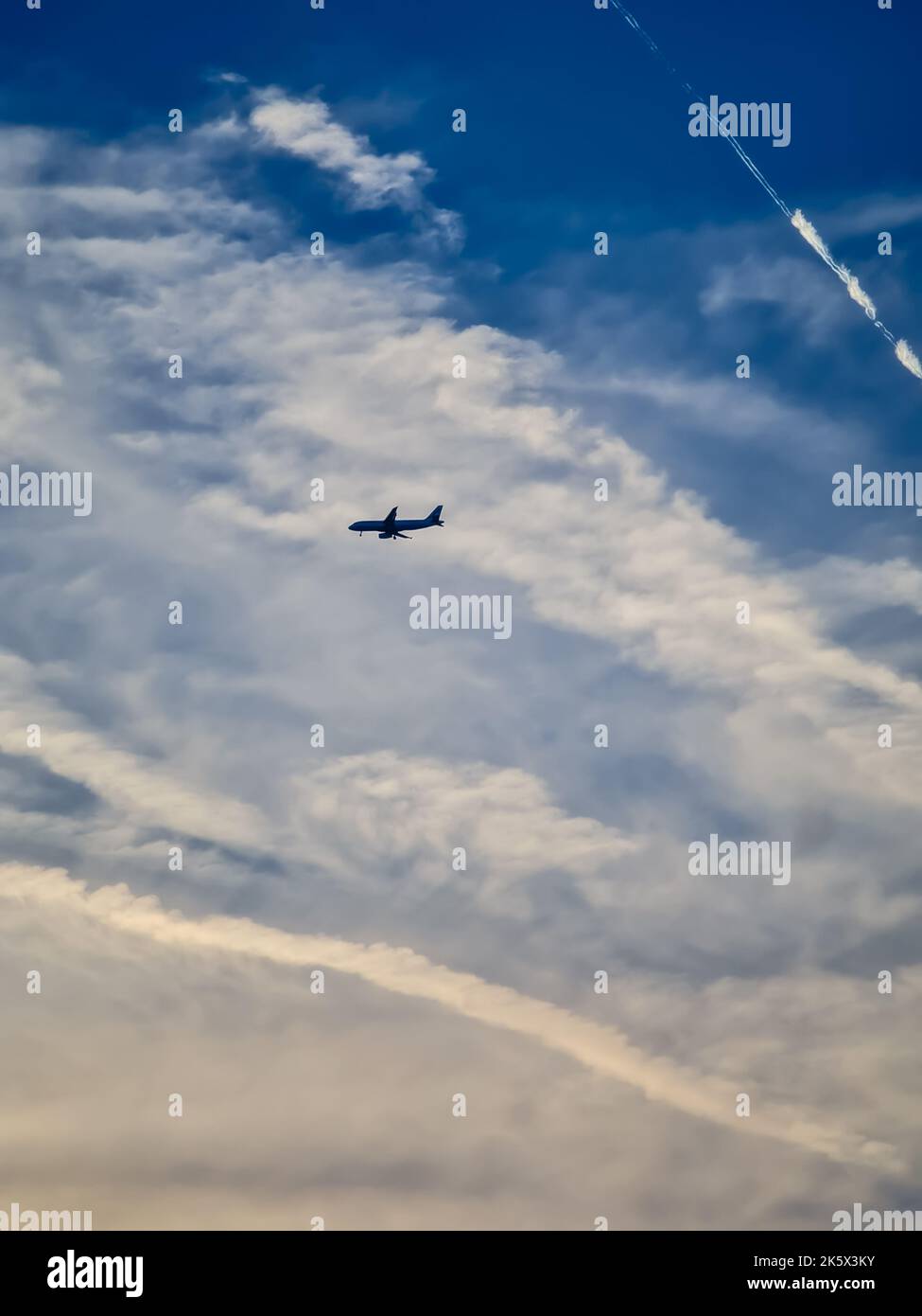 A vertical shot of an airplane in flight in the sky full of clouds ...