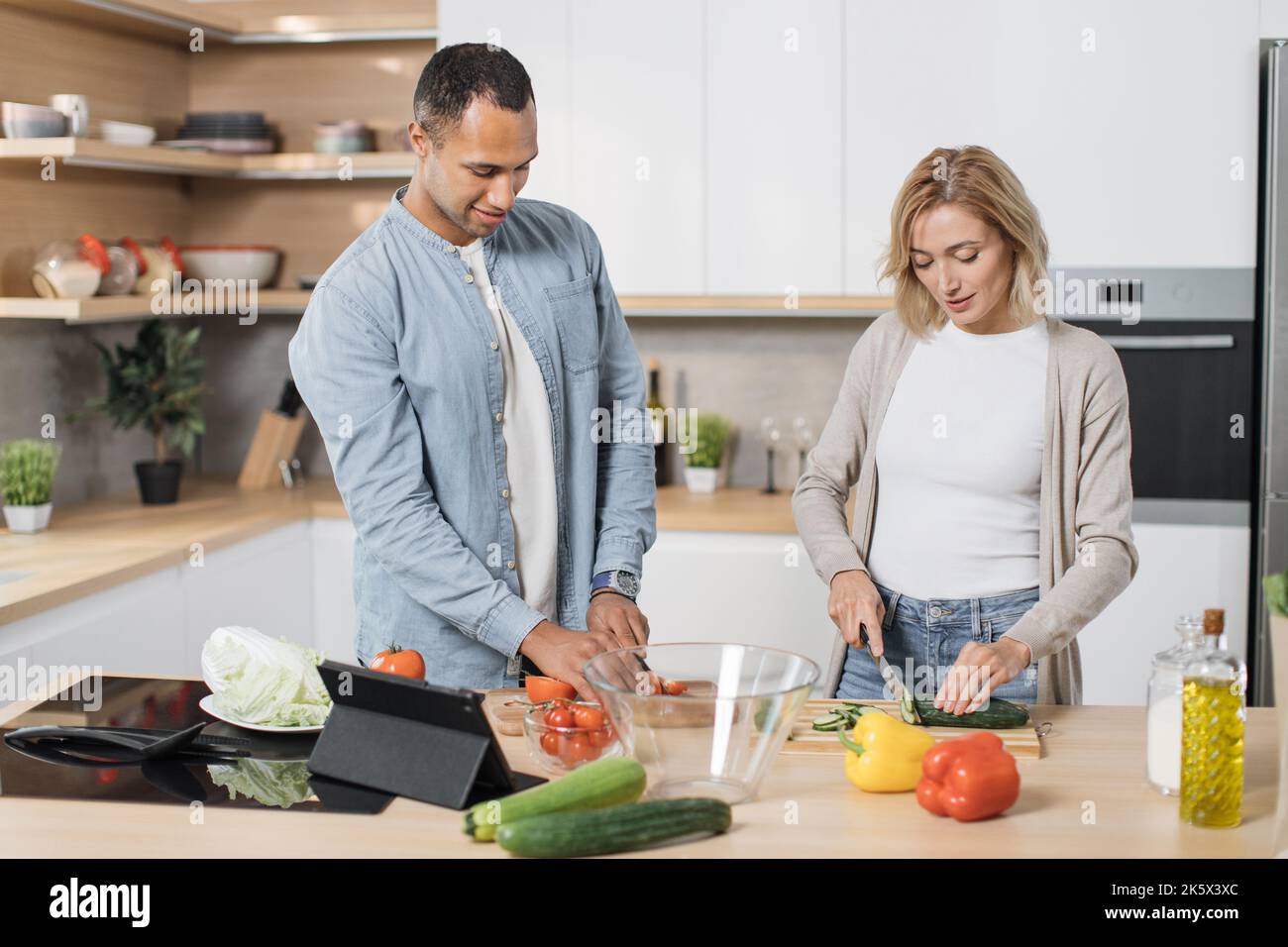 Young attractive couple in love preparing salad from fresh vegetables ...