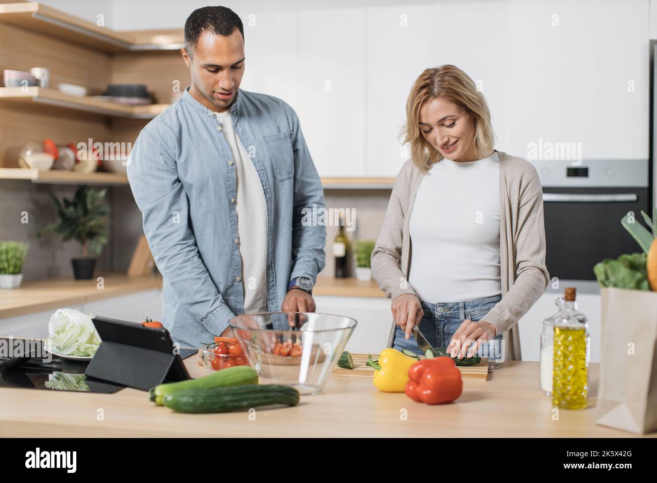 Young attractive couple in love preparing salad from fresh vegetables ...