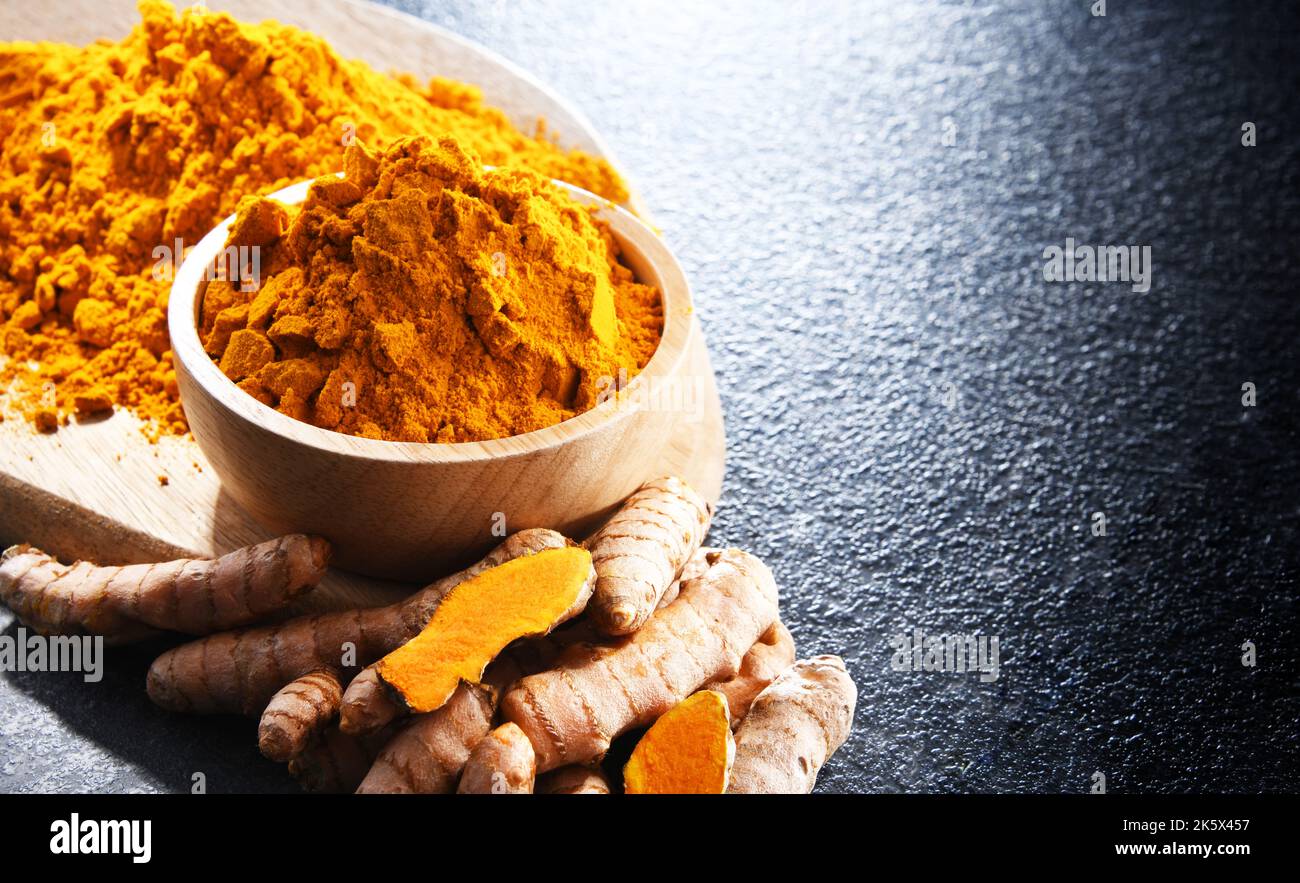 Composition with a bowl of ground turmeric and its fresh rhizome Stock ...