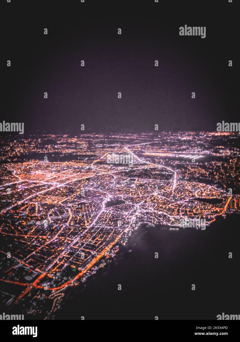 A vertical bird's-eye shot of a cityscape illuminated in the ...