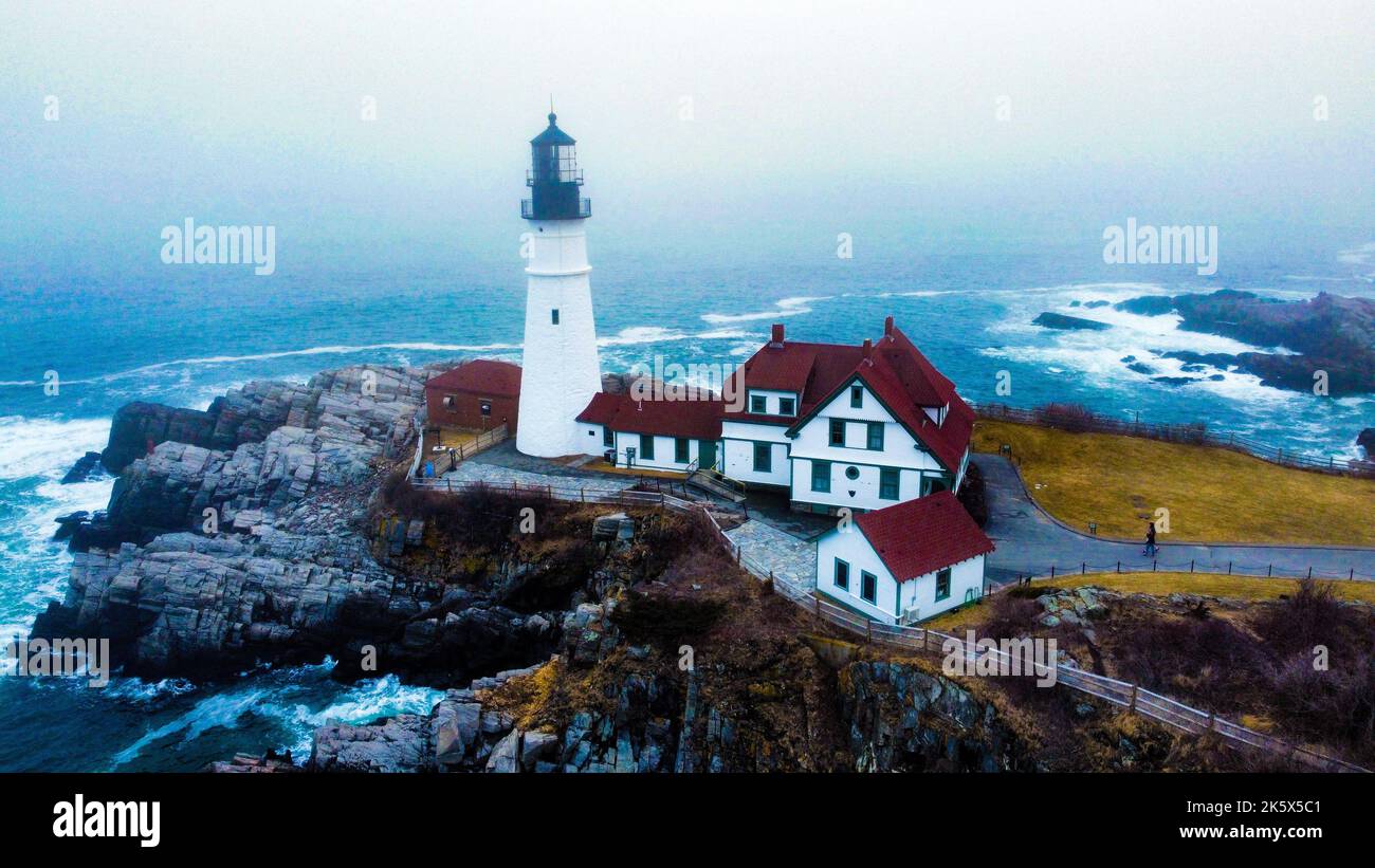 A beautiful view of the Portland Head Light and red roof houses on a ...