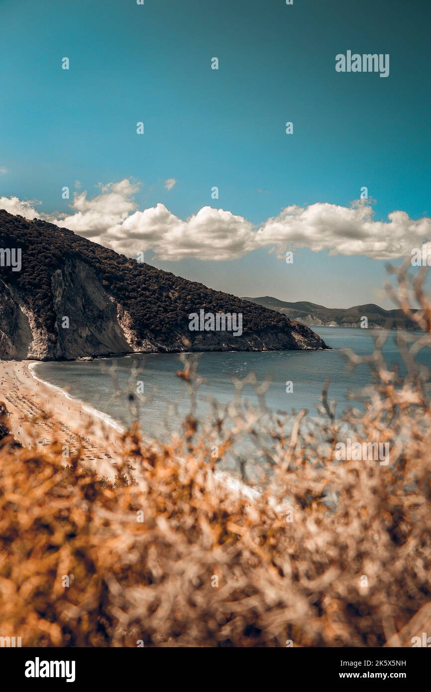 A vertical of a coastline with shallow ocean waves approaching the arid ...
