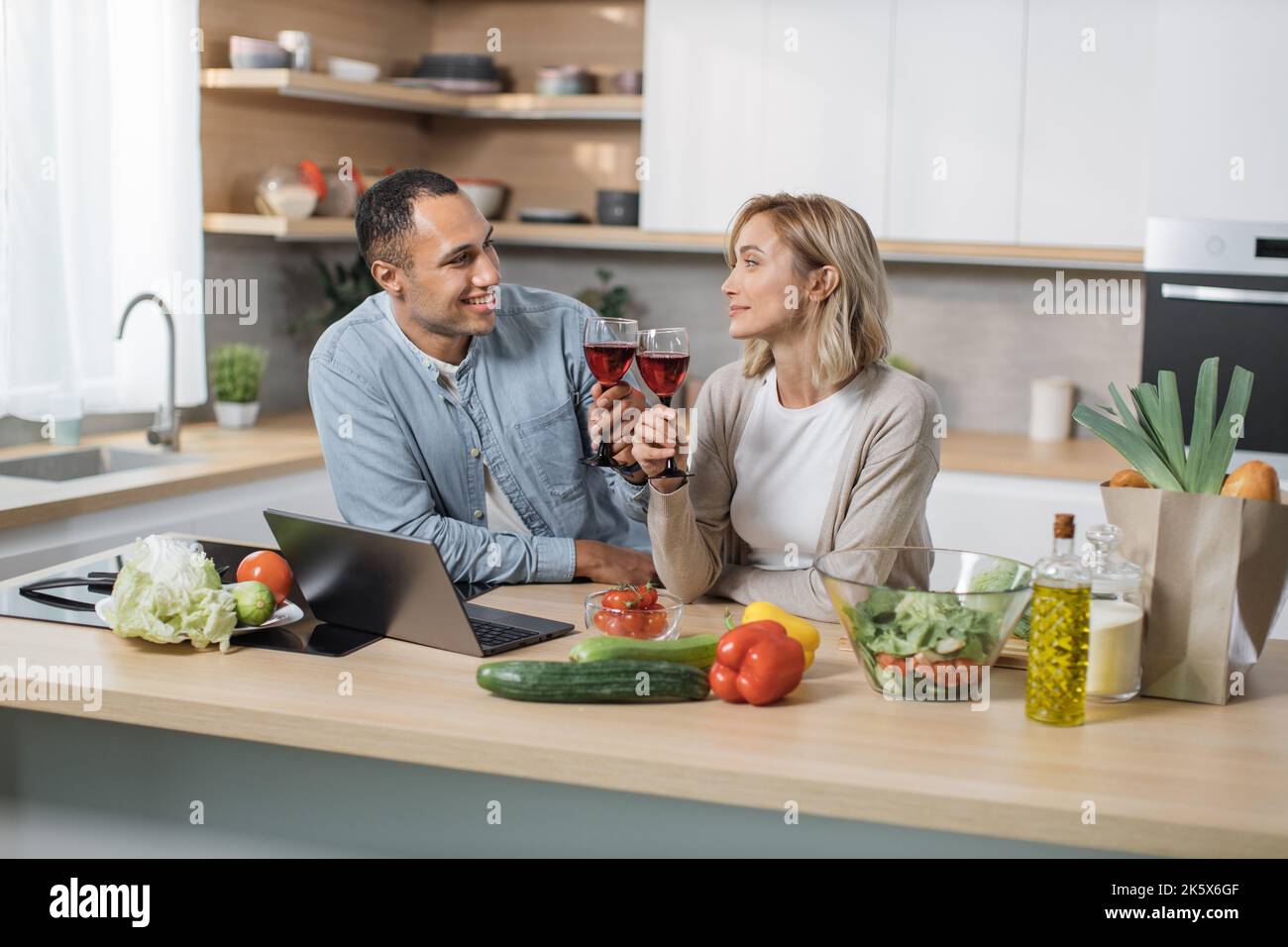 Joyful family cooking dinner at modern light home. Couple in love ...