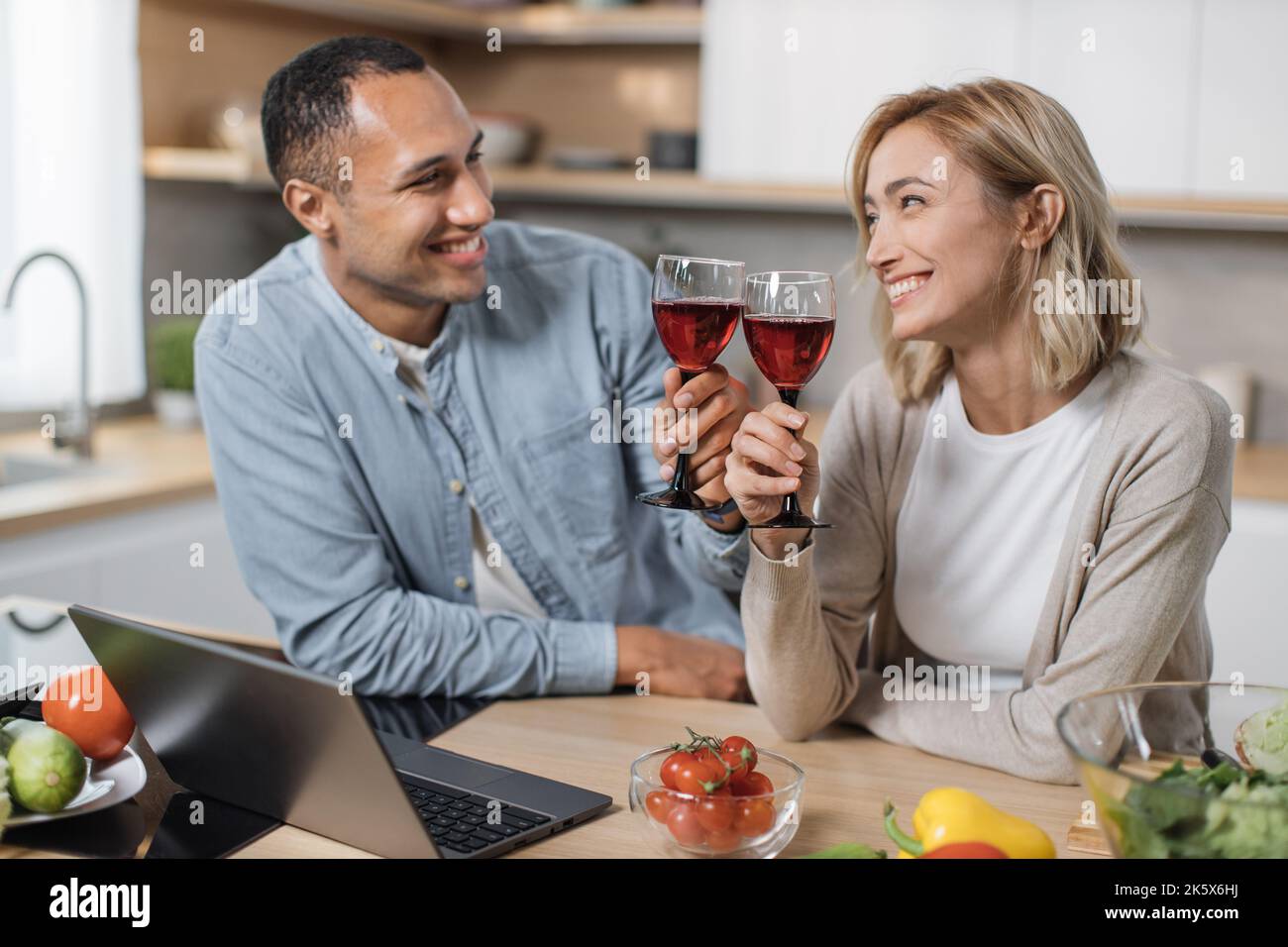 Joyful family cooking dinner at modern light home. Couple in love ...