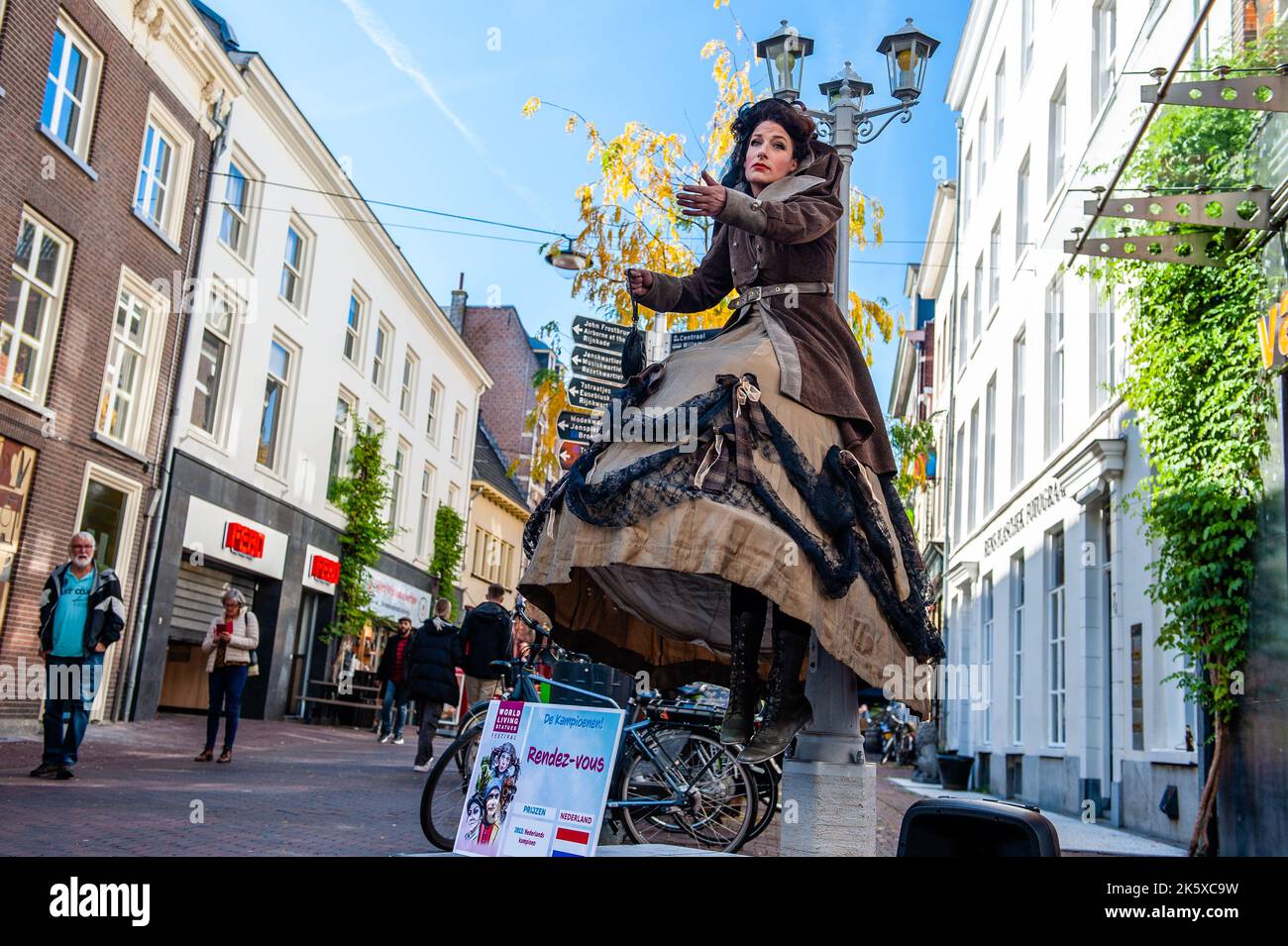A female living statue is seen hanging from a street light as a part of ...