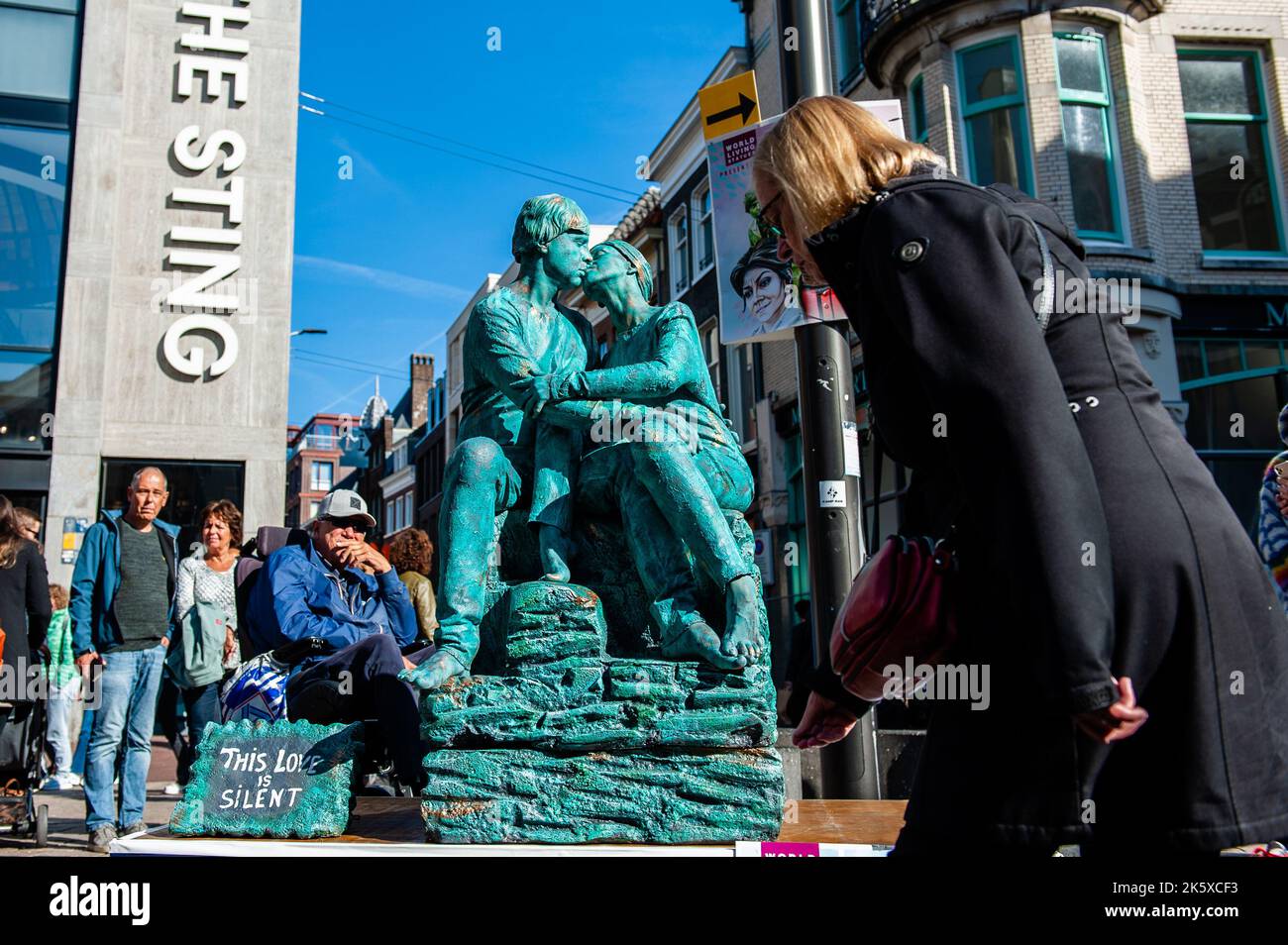 A woman is seen leaving some coins to a couple performing as living ...
