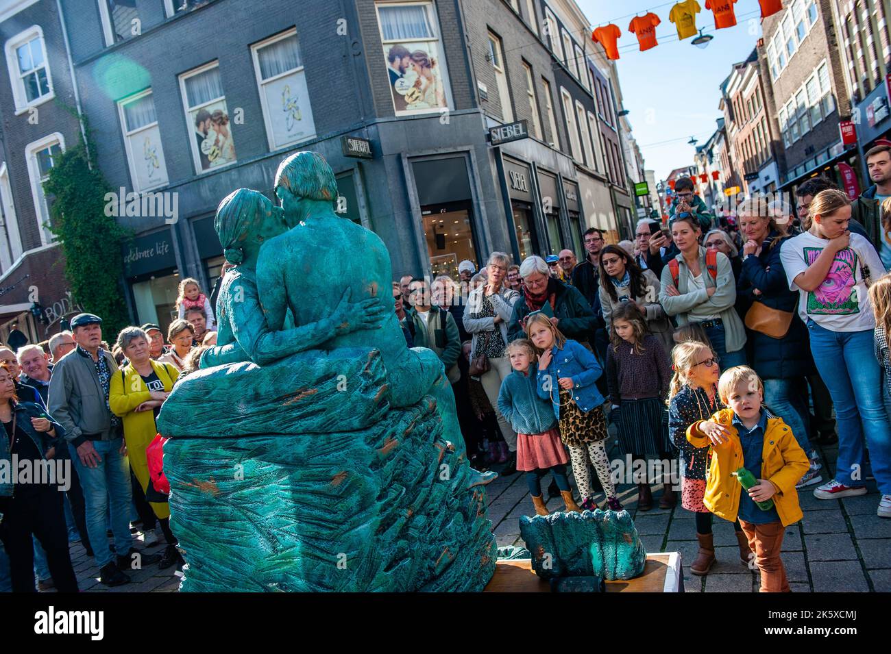 A big audience is seen surrounding one of the living statues performing ...