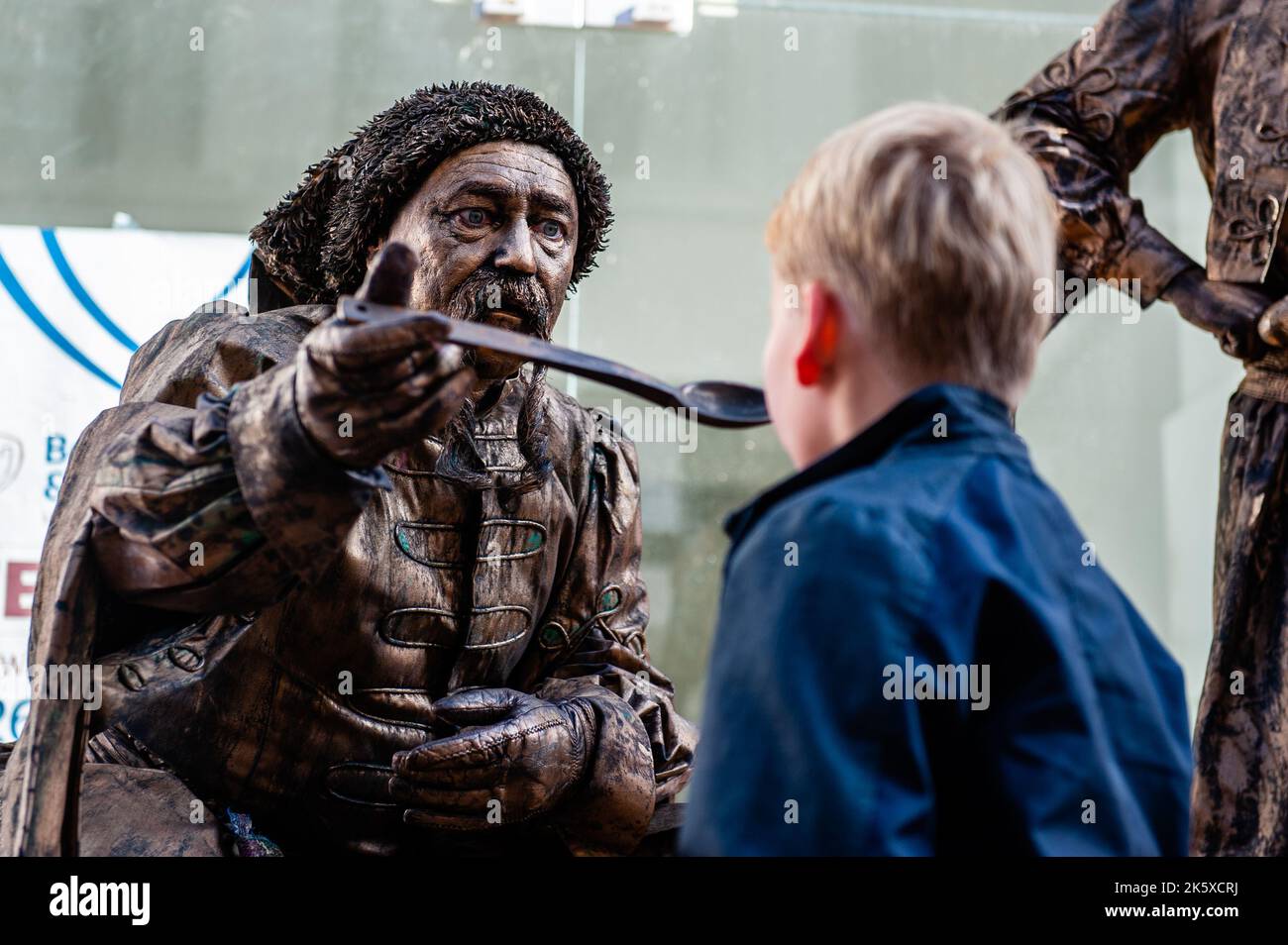 An artist performing as a living statue is seen interacting with a ...