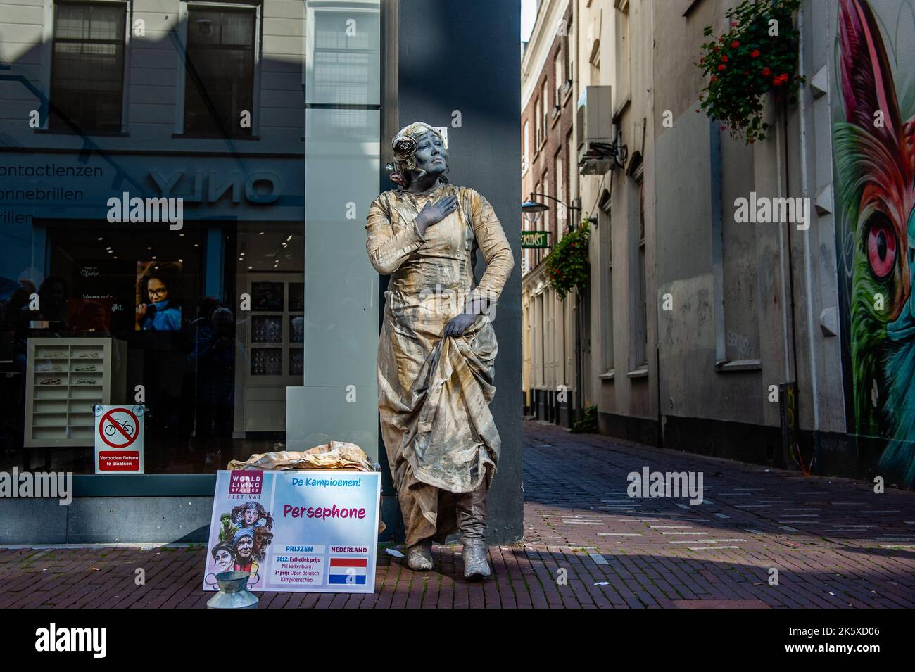 An female artist is seen performing as a living statue is on the street ...
