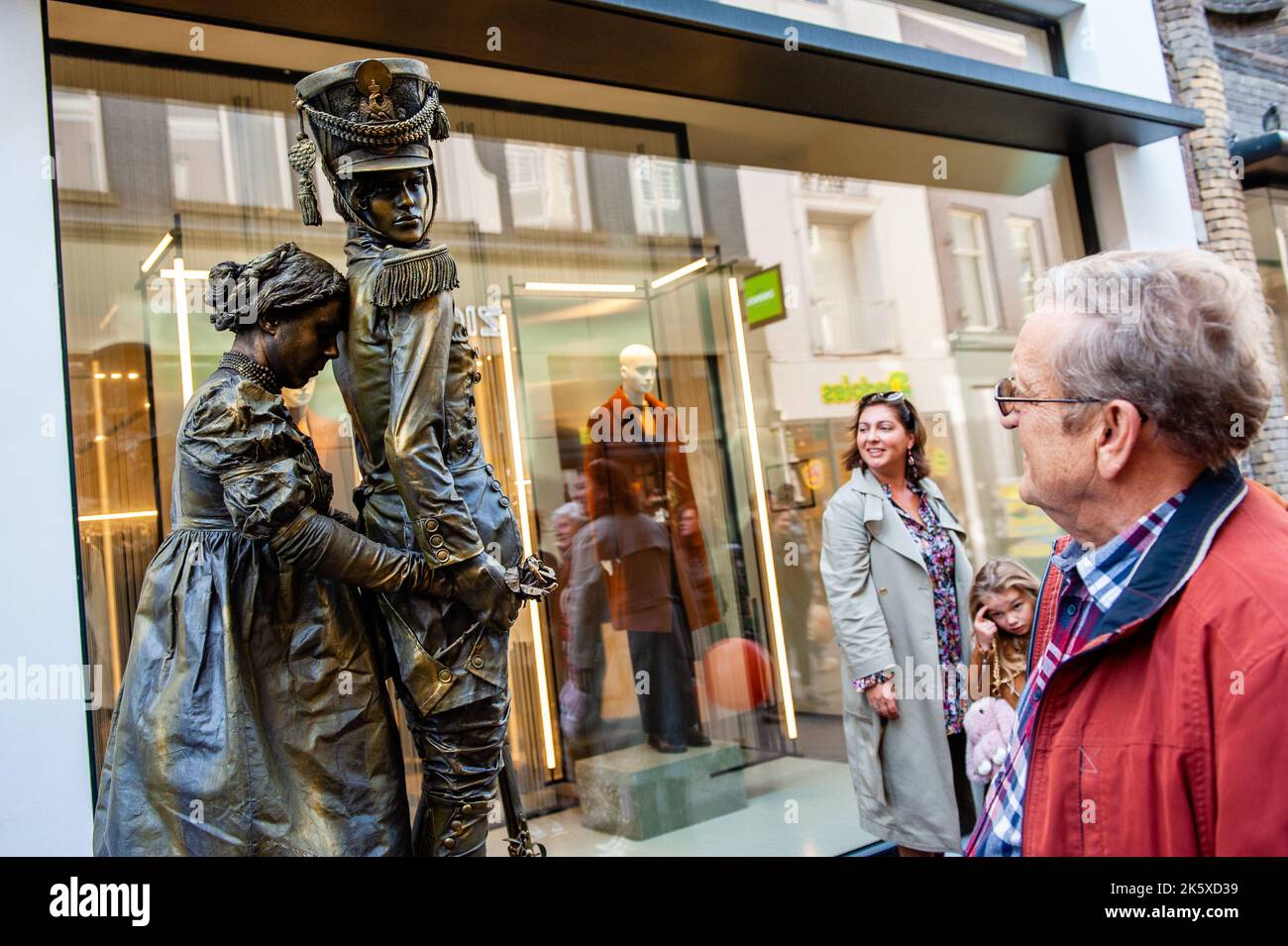People are seen looking at one of the living statues performing on the ...