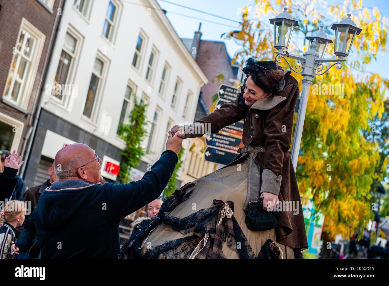 A living statue hanging from a streetlight is seen interacting with an ...