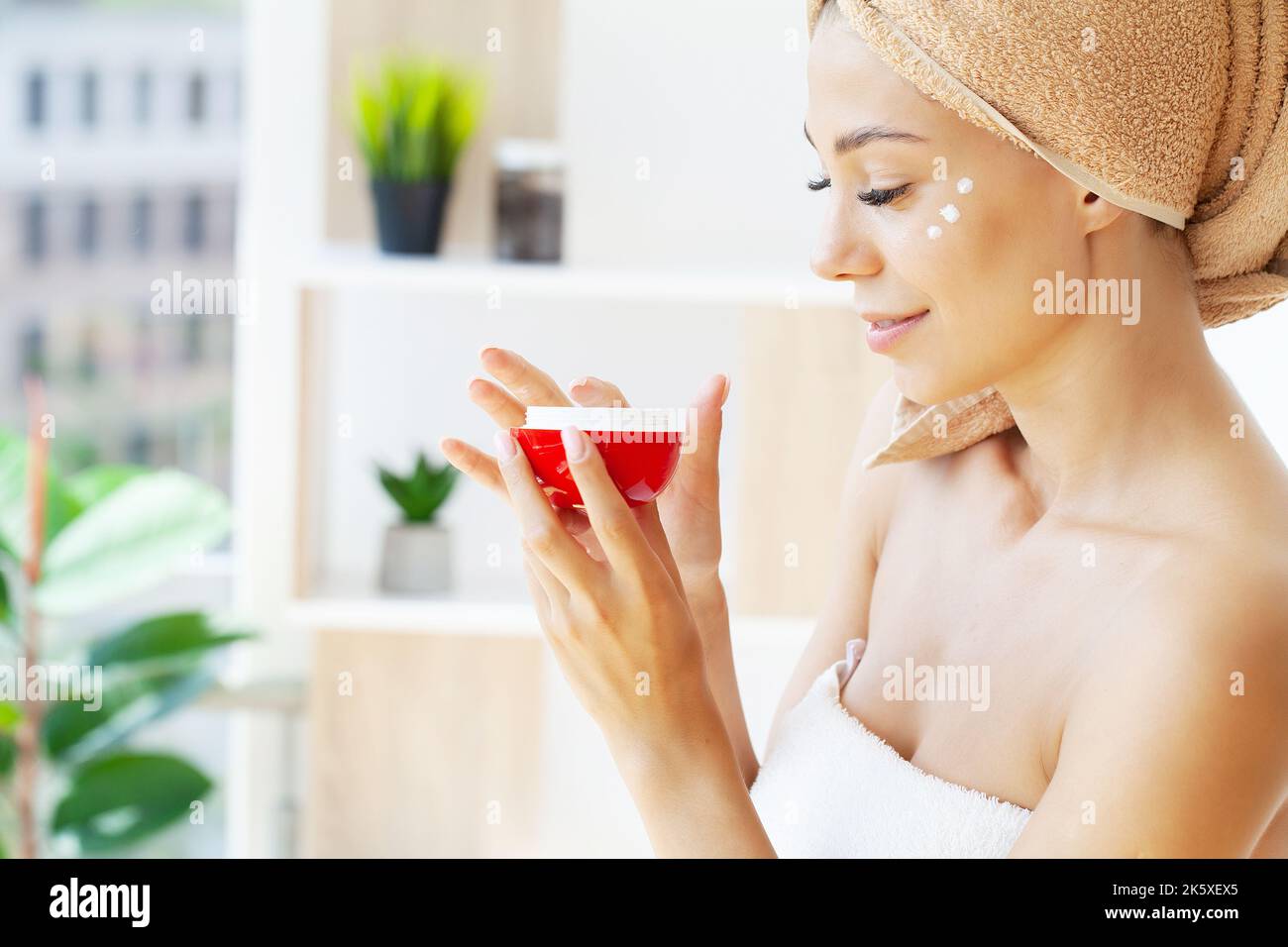 Beautiful woman applying moisturizer cream on her face Stock Photo - Alamy