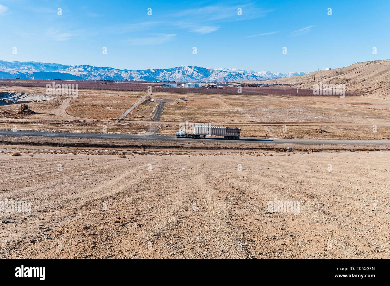A tractor-trailer semi moves down a road in a vast active solid-waste ...