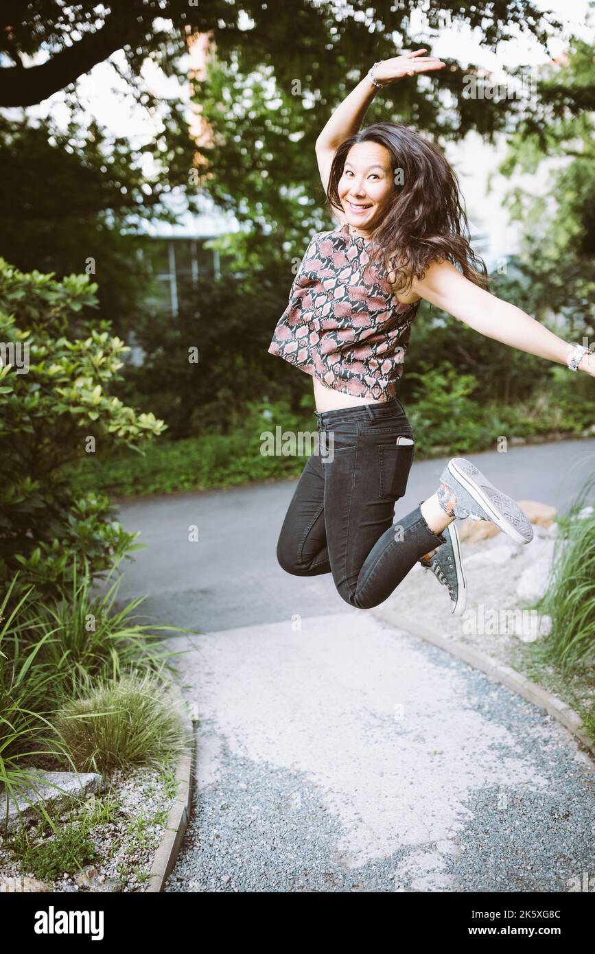 Young happy mixed race Japanese woman in jeans, shirt and sneakers in ...